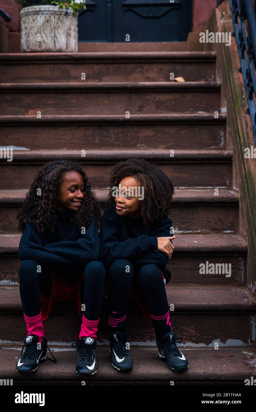 Smiling sisters in sports clothing sitting on steps Stock Photo - Alamy