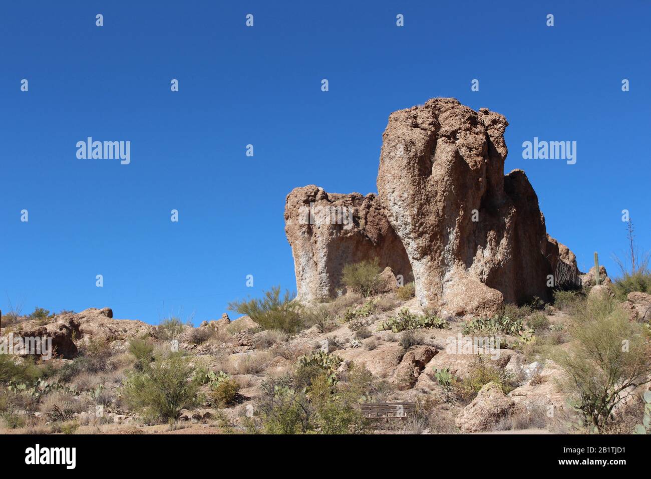 A wood bench alongside a hiking trail through the mountainous, desert ...