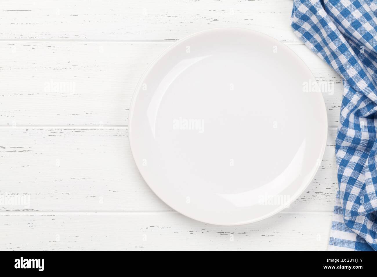 Kitchen table with empty plate, tablecloth and space for your recipe or ...