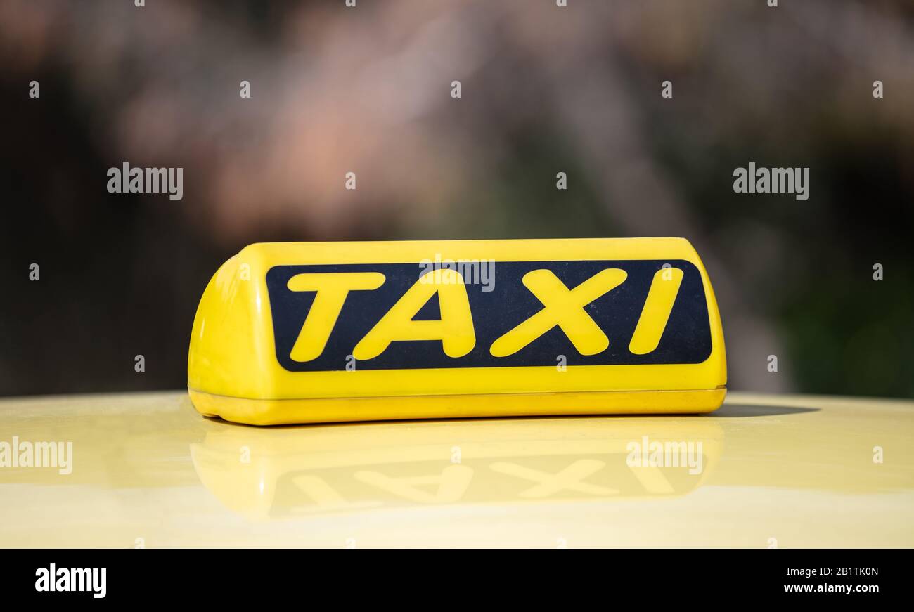 Taxi sign on a car roof, yellow and black color text, closeup view ...