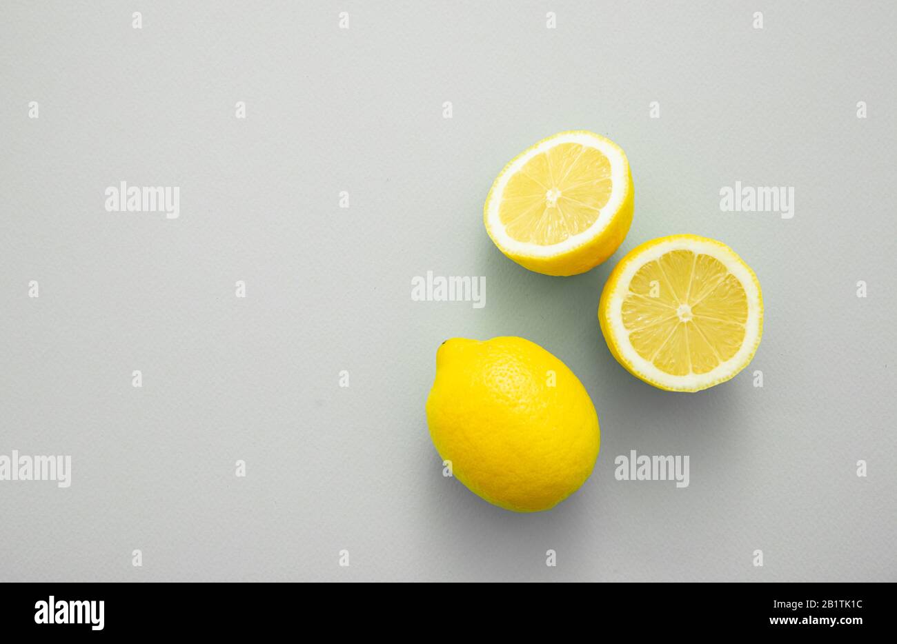 Ripe juicy lemons on gray background. Whole yellow lemon and lemon cut ...