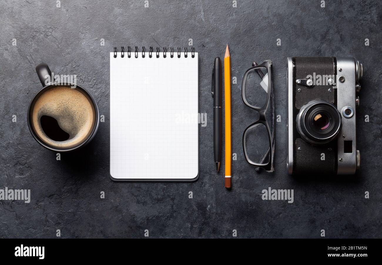 Office desk table with camera, supplies and coffee. Dark workspace ...
