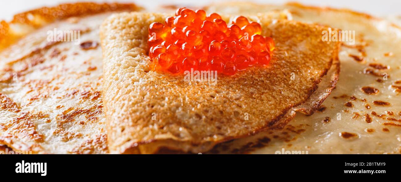 Traditional Russian Crepes Blini stacked in a plate with red caviar on ...