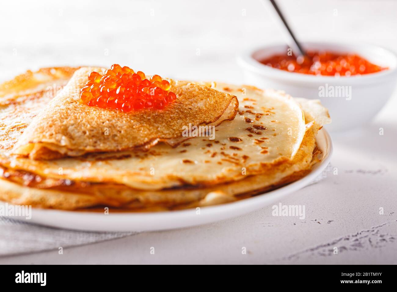 Traditional Russian Crepes Blini stacked in a plate with red caviar on ...