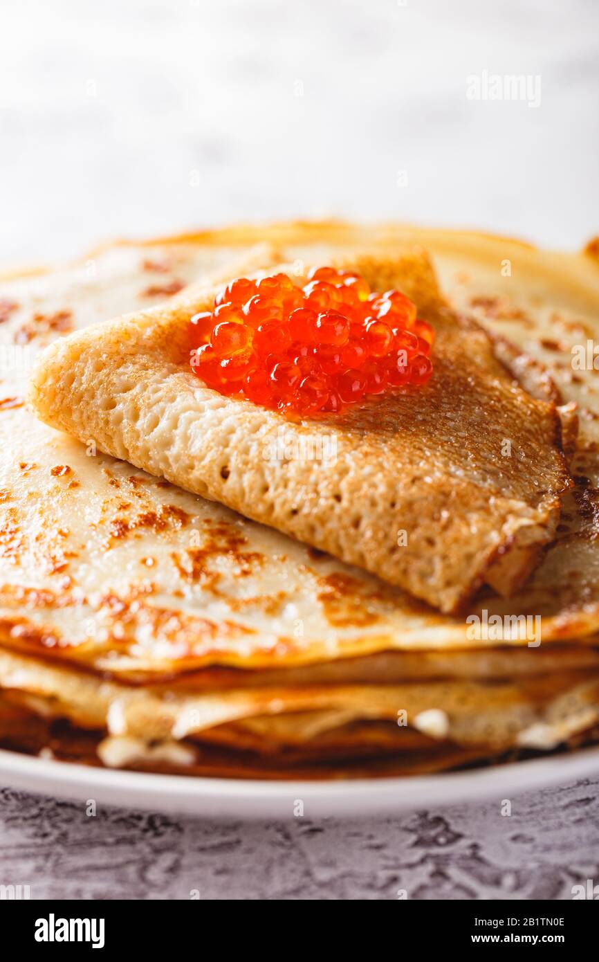 Traditional Russian Crepes Blini stacked in a plate with red caviar on ...
