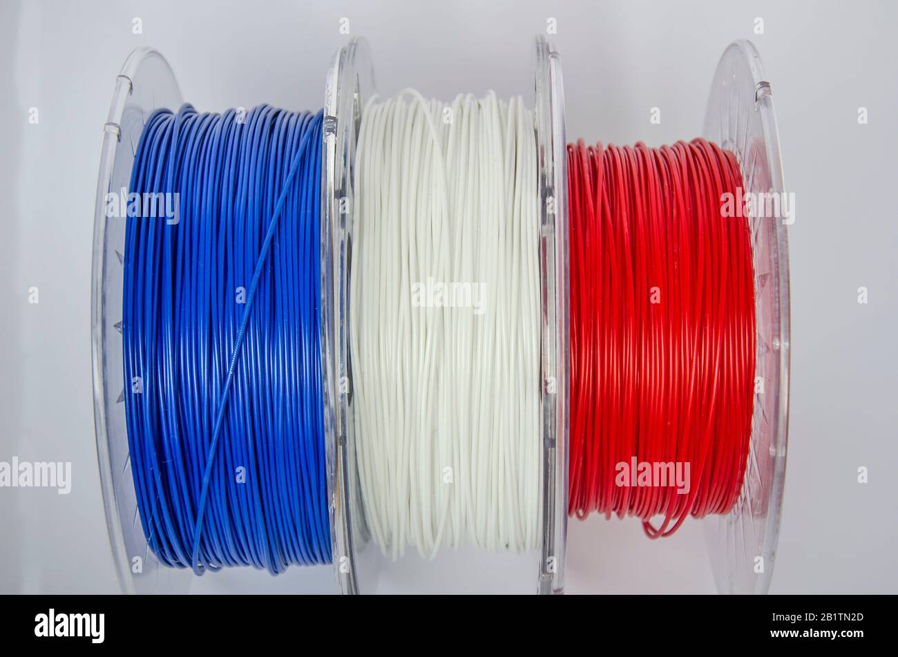 Close up view of coils of plastic for 3D printing. Red, white and blue ...
