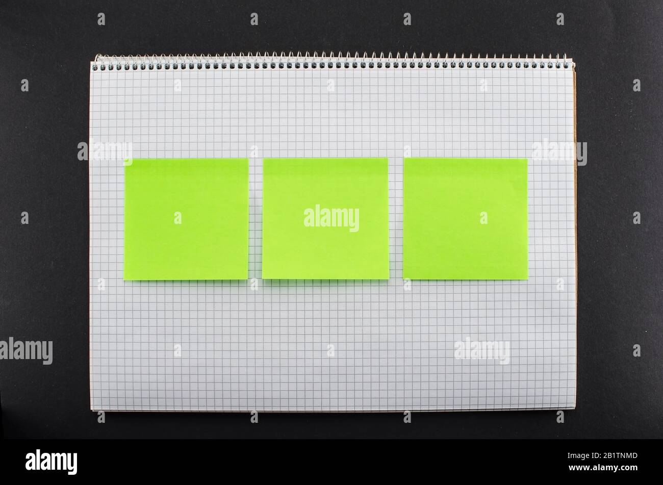 Blank notepad with three empty green sticky notes on black background ...