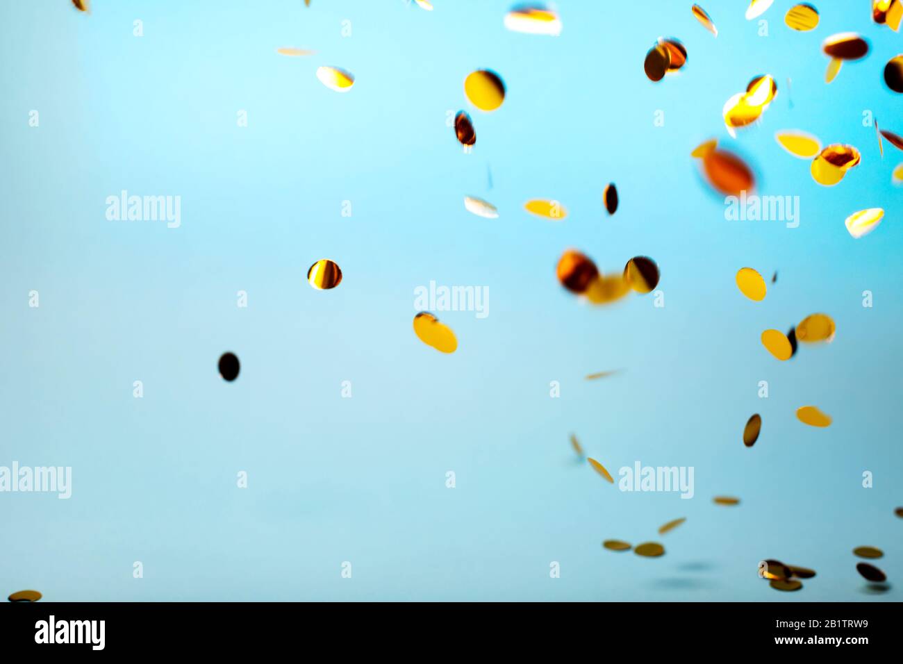 Orange and yellow falling confetti on blue background Stock Photo - Alamy