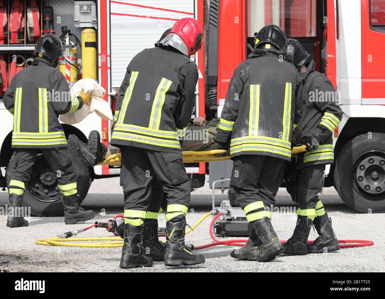 firemen in uniform with the stretcher and the injured after the road ...