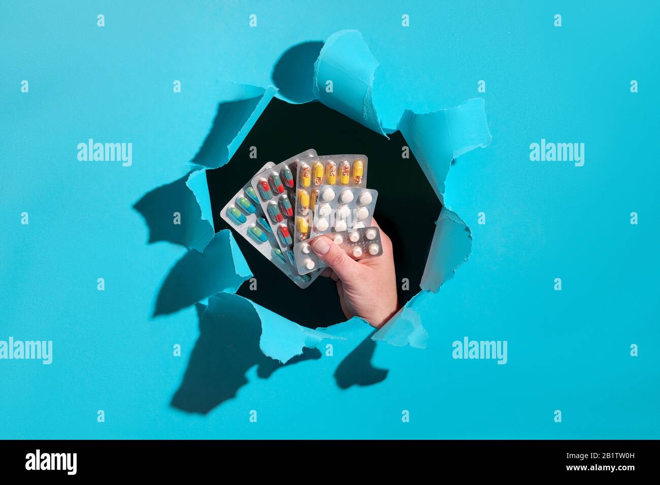 Assorted pills or capsules with medications in hand framed by paper ...