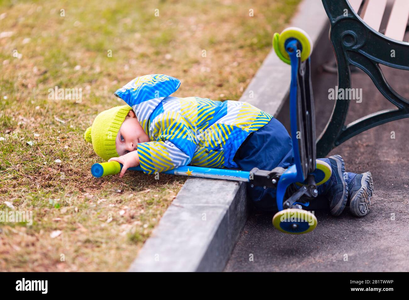 Cute little boy falling off his scooter . Kid getting hurt while riding ...