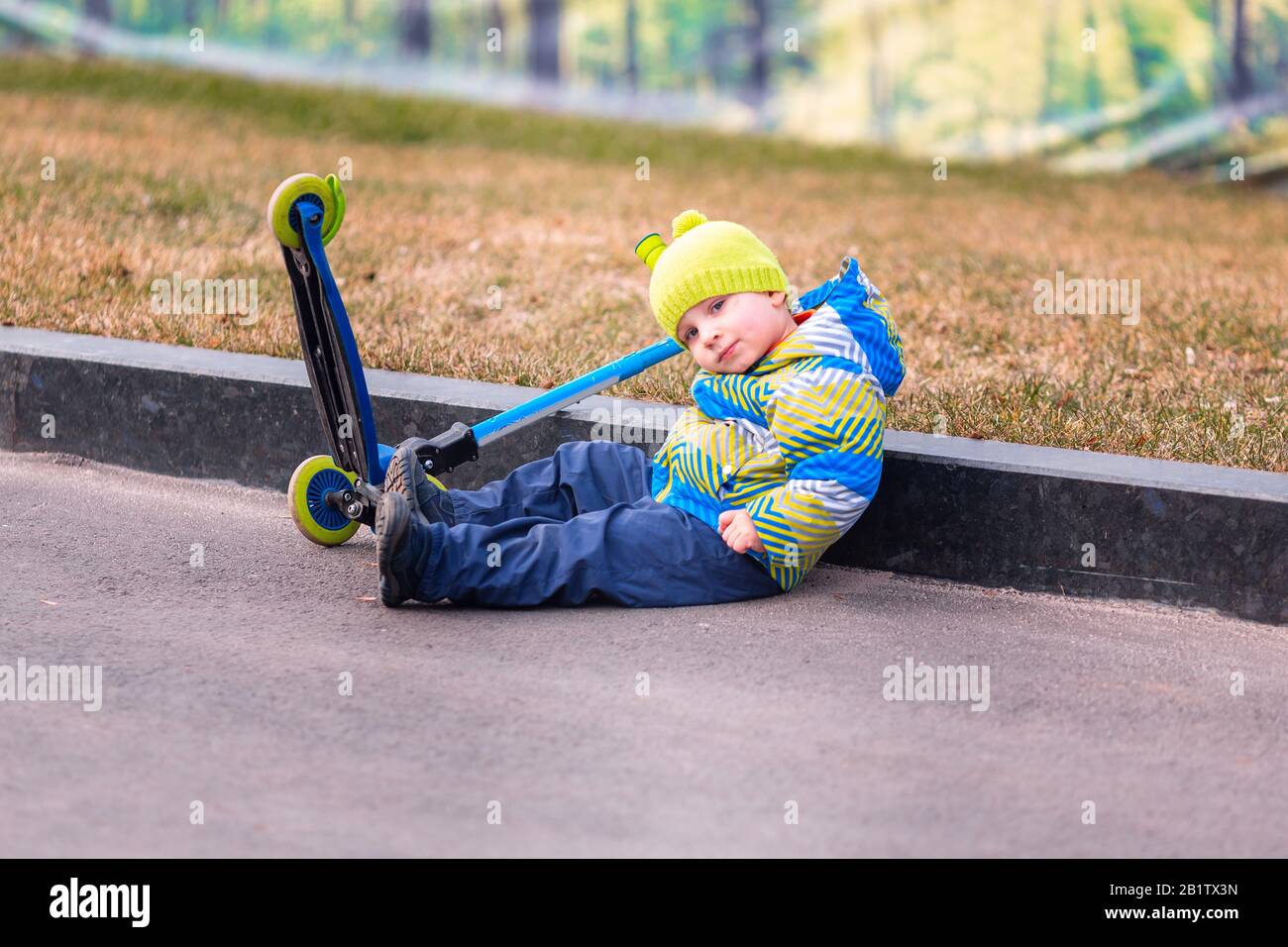 Cute little boy falling off his scooter . Kid getting hurt while riding ...
