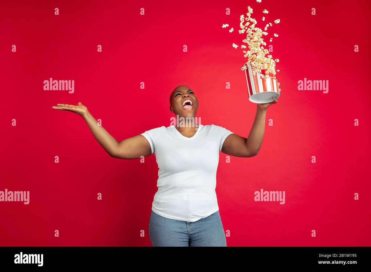 Astonished. Flying popcorn. African-american young woman's portrait on ...