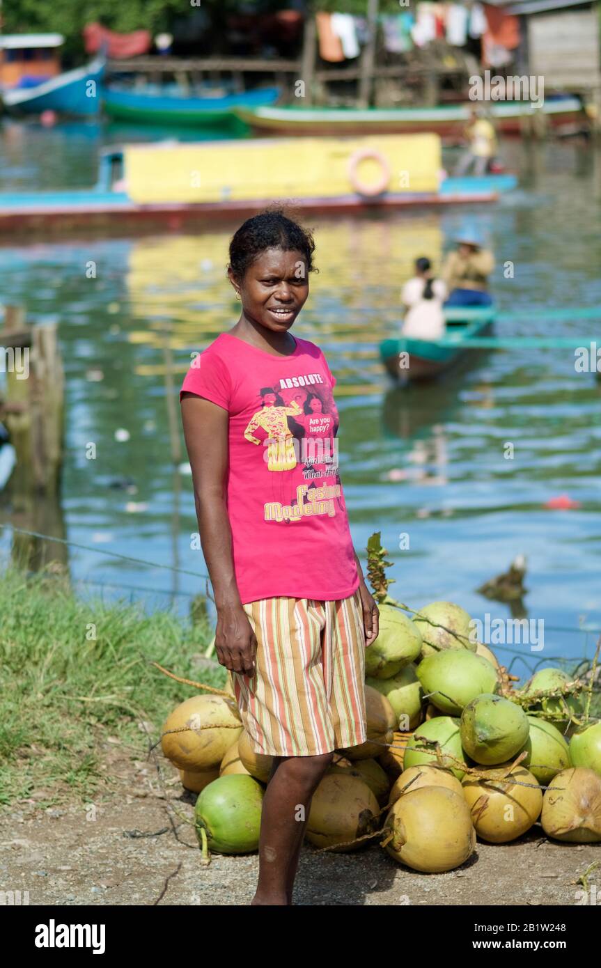 Papua woman carrying coconuts and waiting for the ferryman to cross the ...