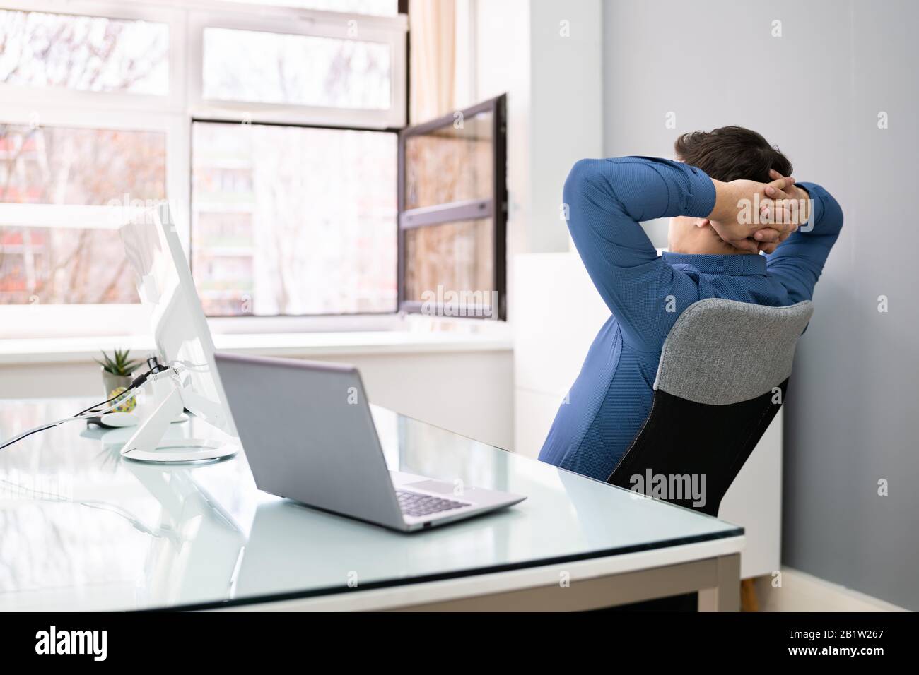 Relaxed Young Businessman Relaxing On Chair Behind Desk At Office Stock ...