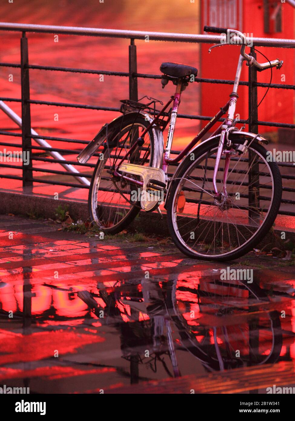 Bicycle leaning against a railing in rainy weather Stock Photo - Alamy