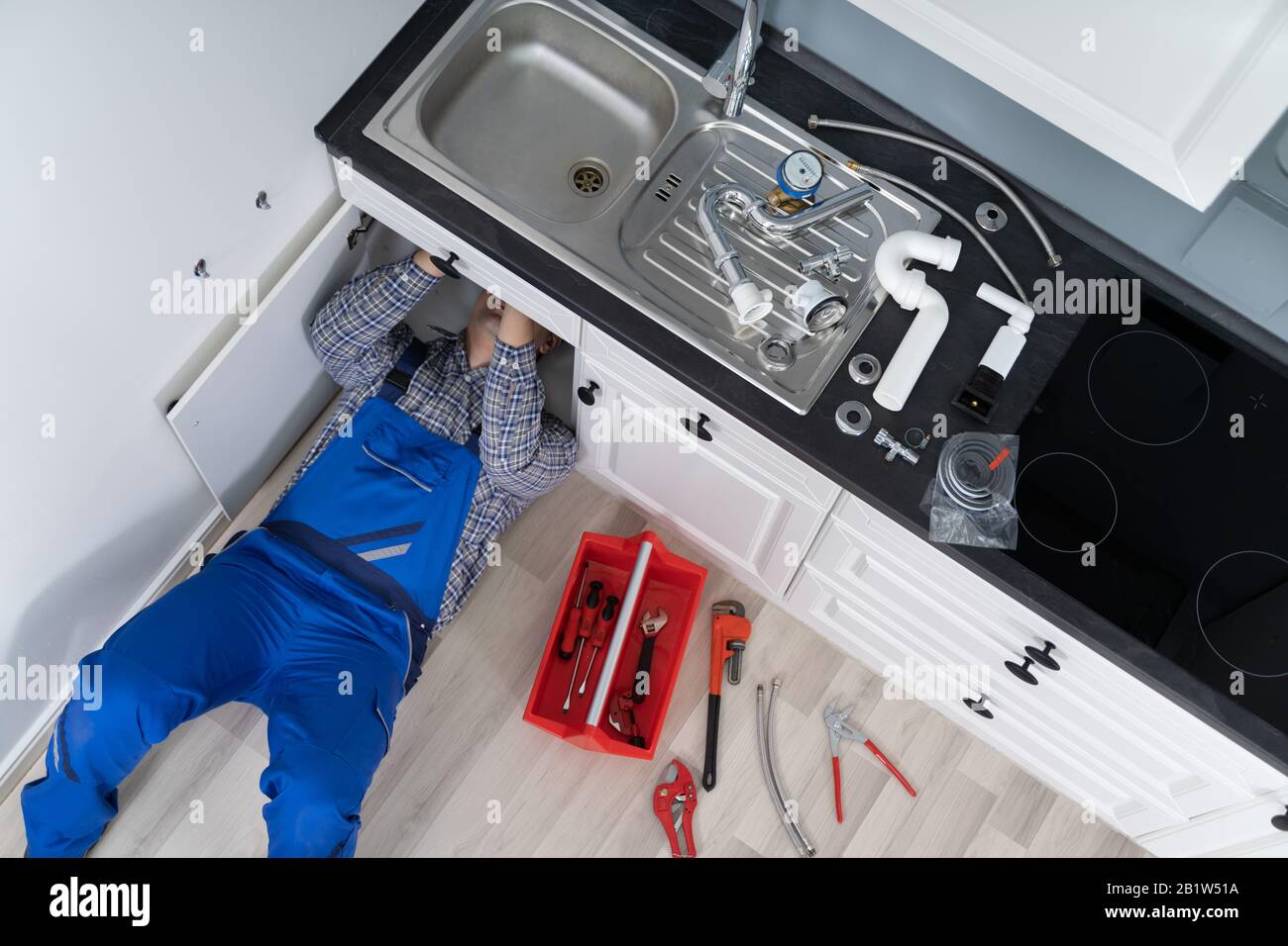 Worker Lying On Floor Repairing Kitchen Sink With Adjustable Wrench ...