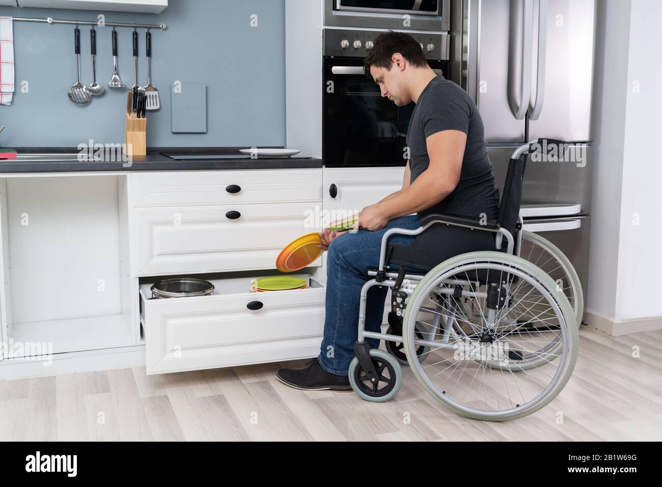 Young Happy Disabled Man Sitting On Wheelchair Arranging Plates In ...