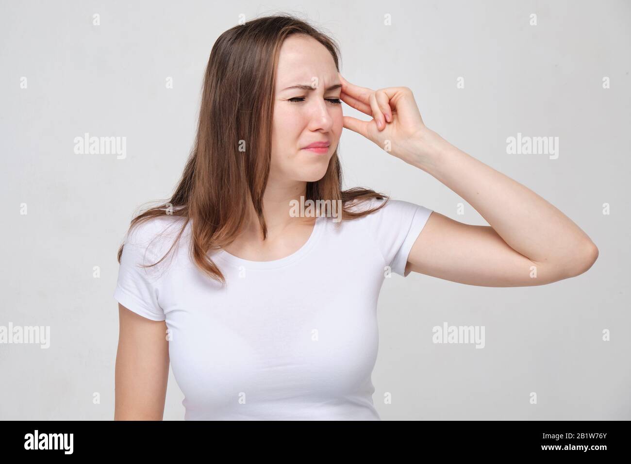 A girl in a white T-shirt is tormented by dizziness and disorientation ...