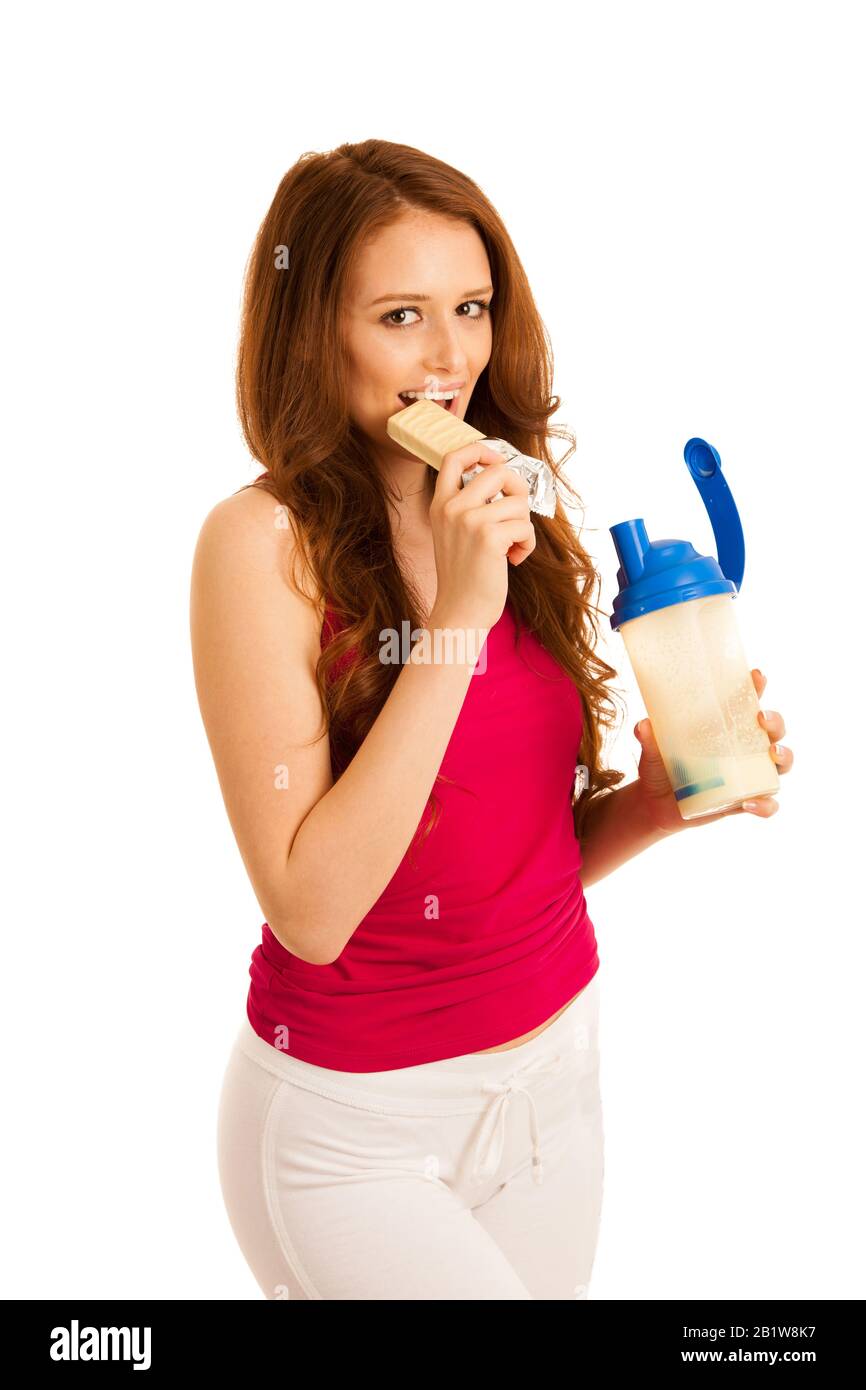 attractive beautiful sporty woman eats protein bar and drinks protein ...