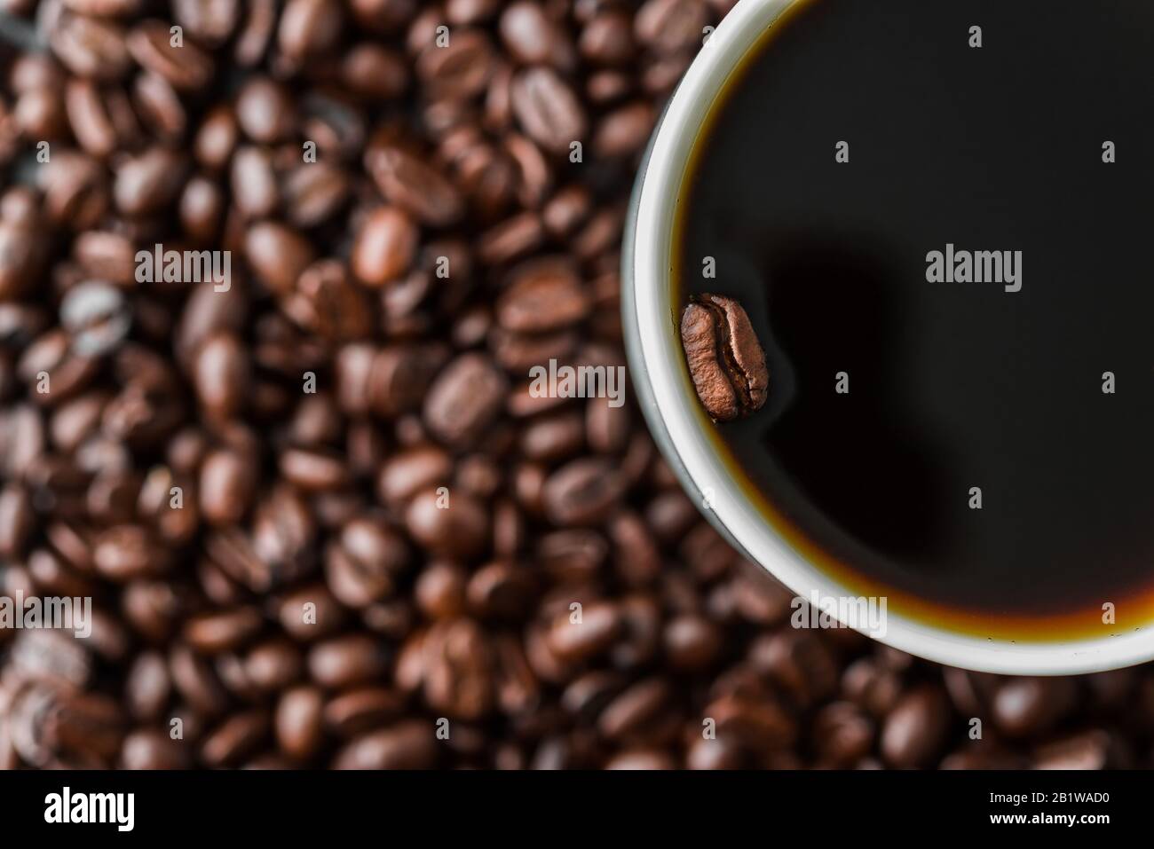 A coffee bean floating in a cup of black coffee Stock Photo - Alamy