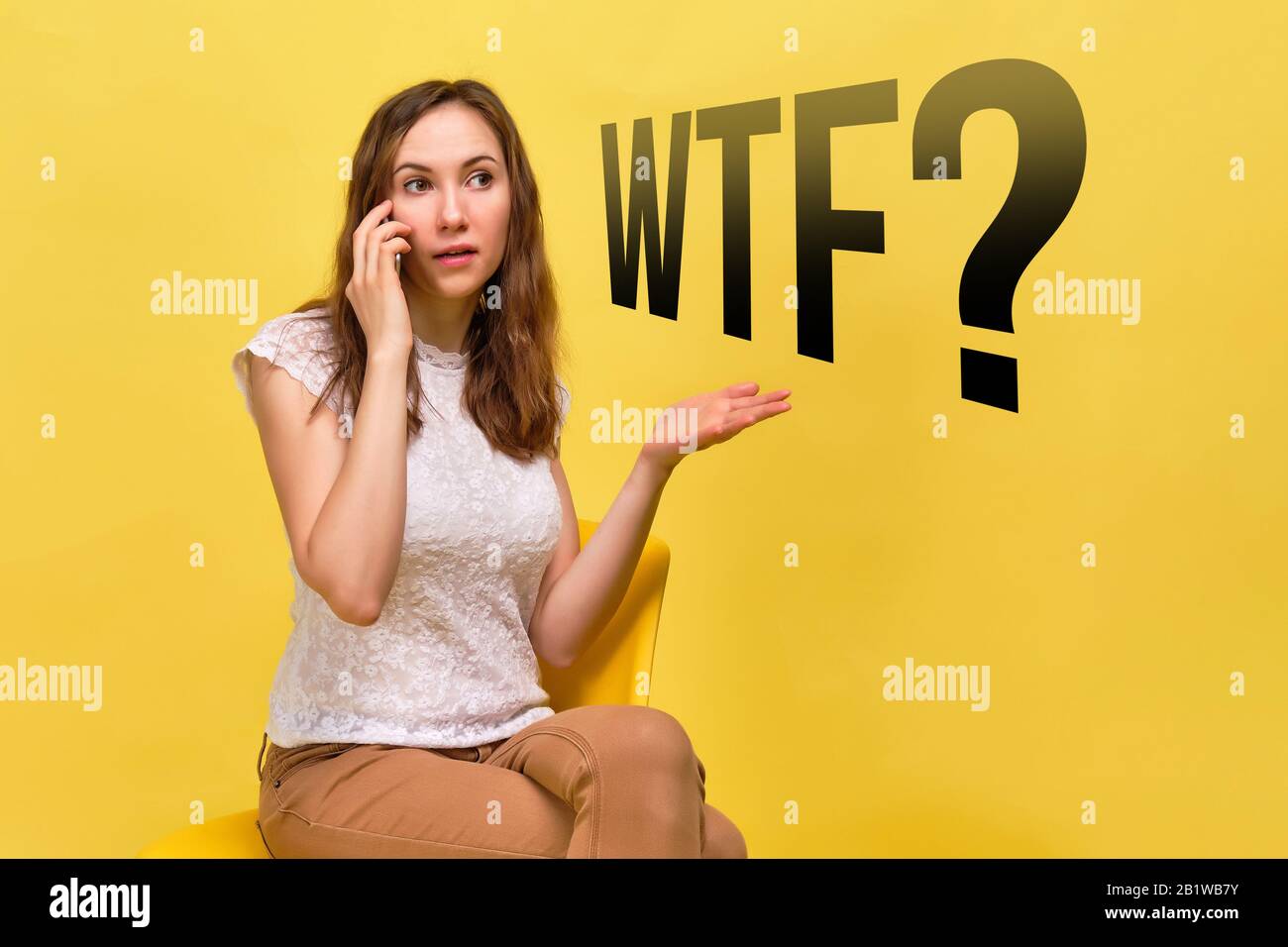 A girl in summer clothes on a yellow background sits and swears on the ...