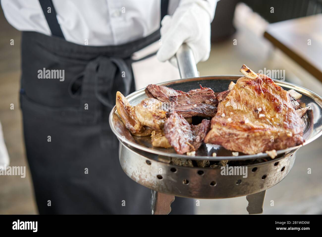 The waiter is holding a plate Various grilled meat set. Barbecue ...