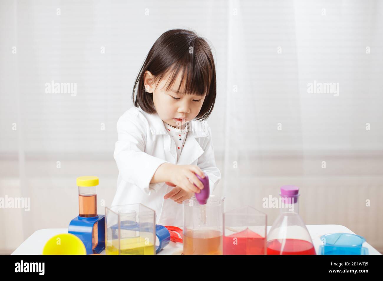 toddler girl pretend play scientist role at home against white ...