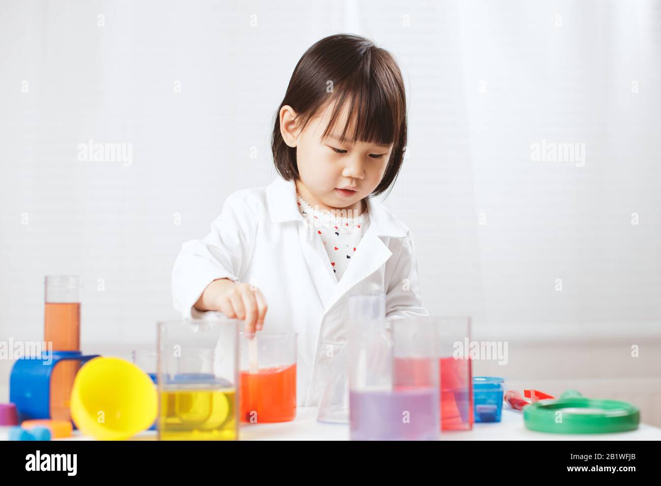toddler girl pretend play scientist role at home against white ...
