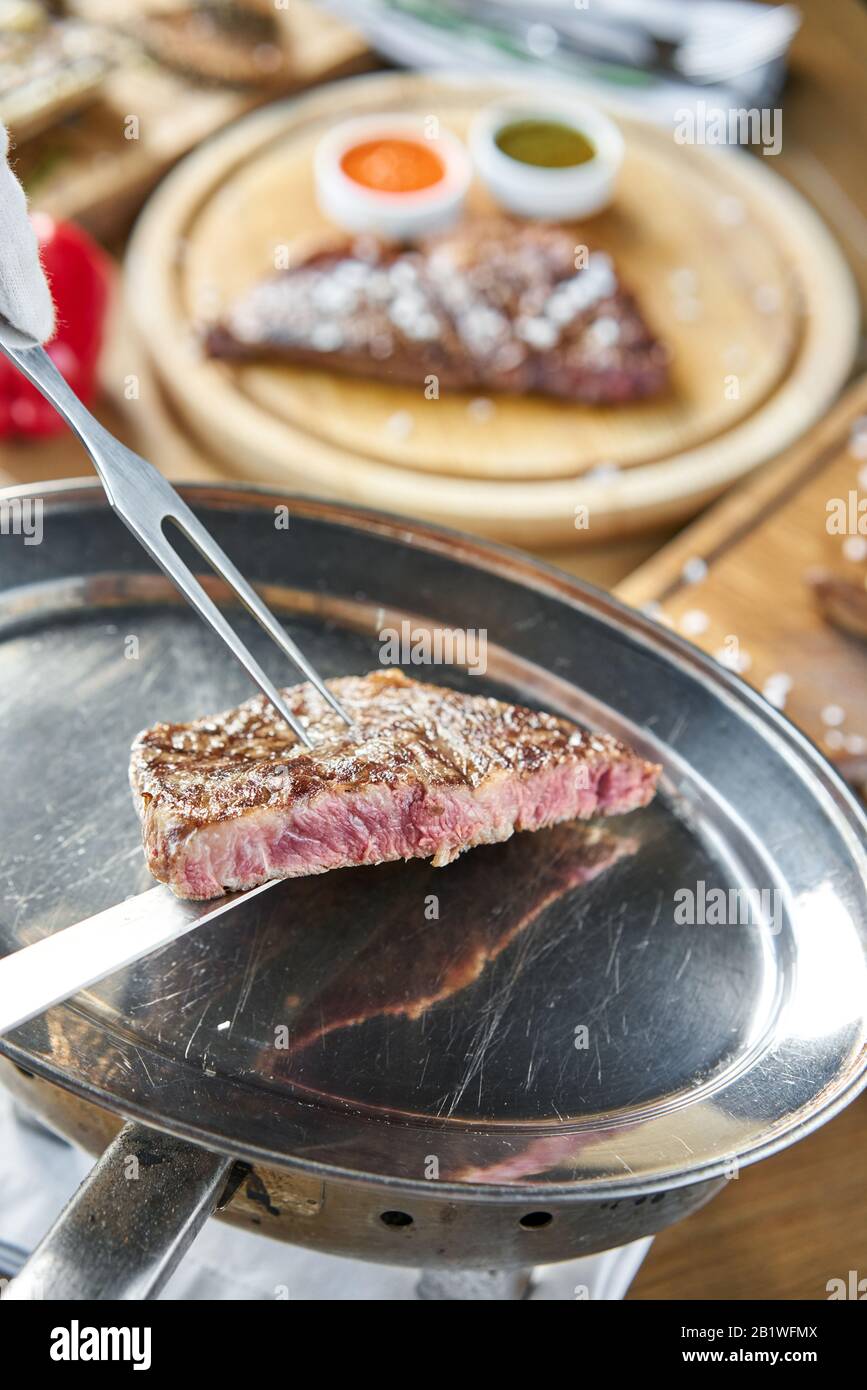 The waiter is holding a plate Grilled striploin steak with Pickled ...
