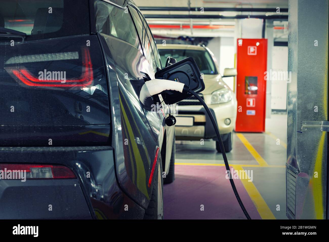 Electric car at charging station indoor underground parking in basement ...