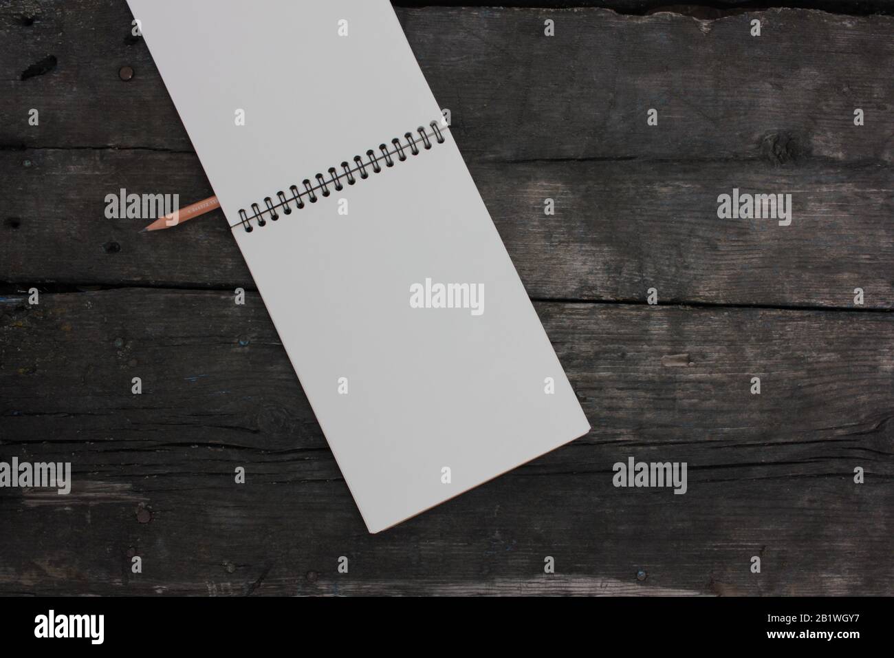 Open paper notepad on spiral and pencil on rough textured wooden table ...