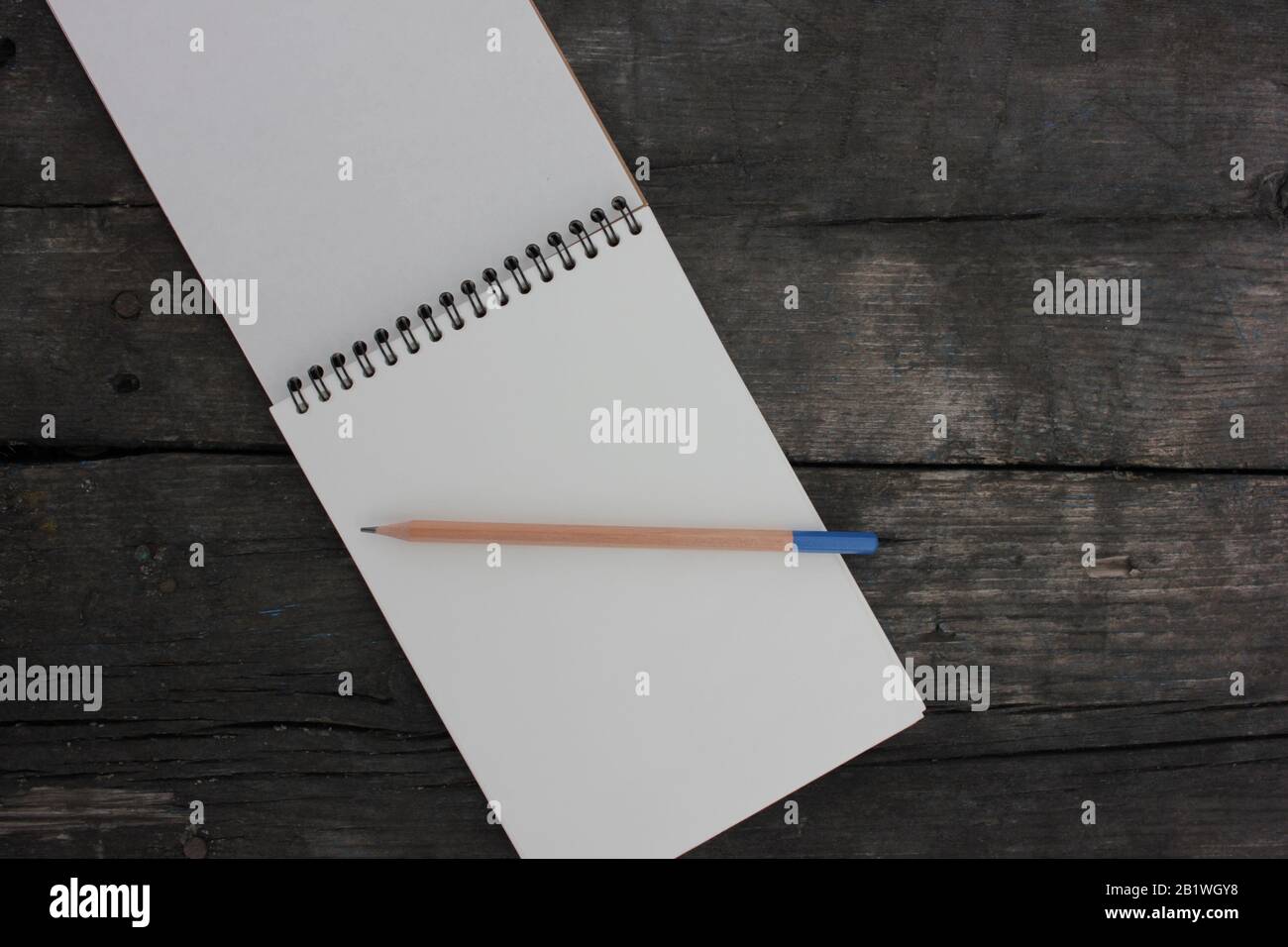 Open paper notepad on spiral and pencil on rough textured wooden table ...