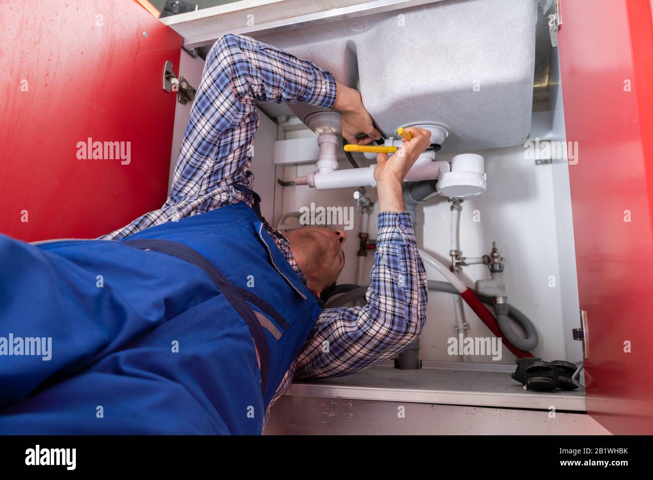 Young Plumber Working With Pipe Wrench In Kitchen Stock Photo - Alamy