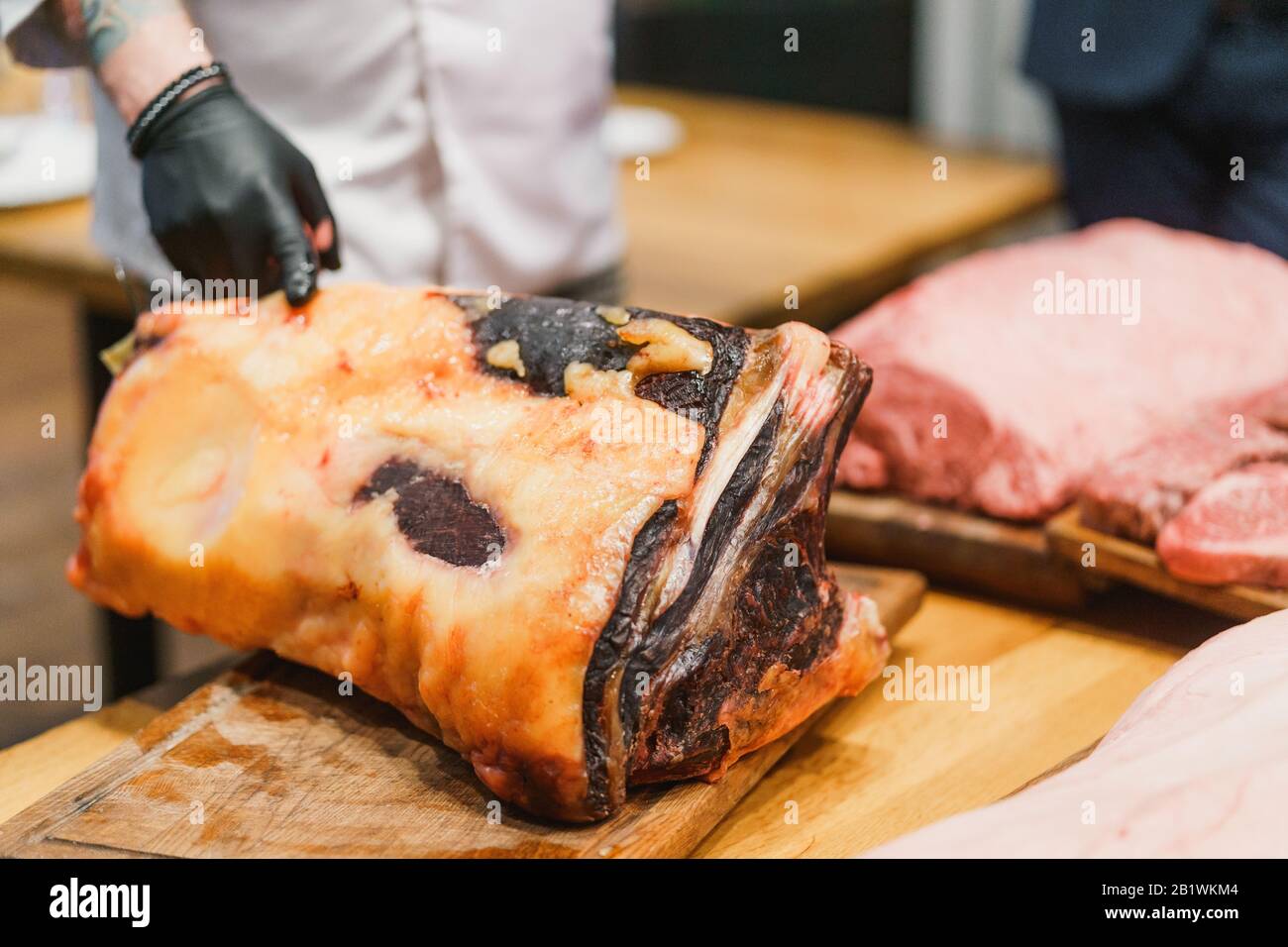 Butcher demonstrating cured and raw meat at a restaurant Stock Photo ...