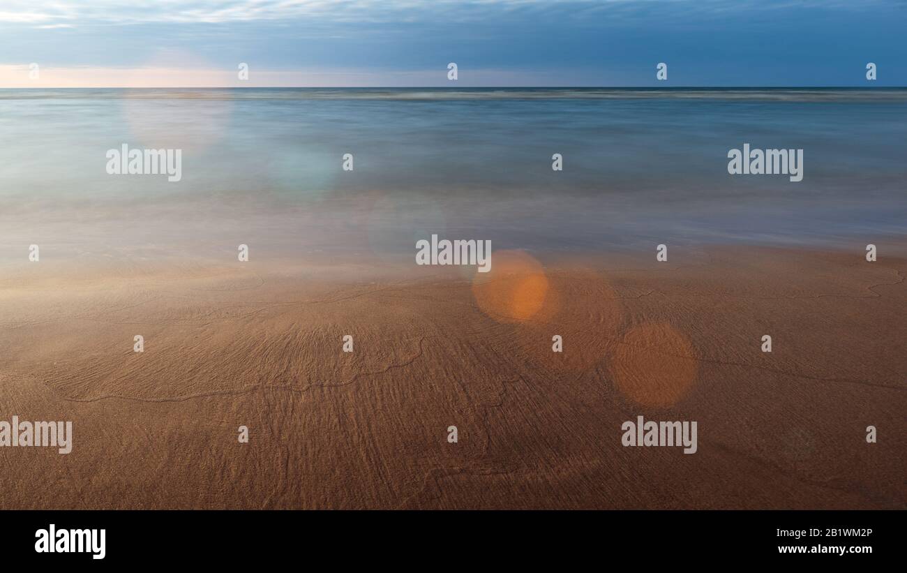 Long exposure of colourful sunset on the beach with sky motion for ...