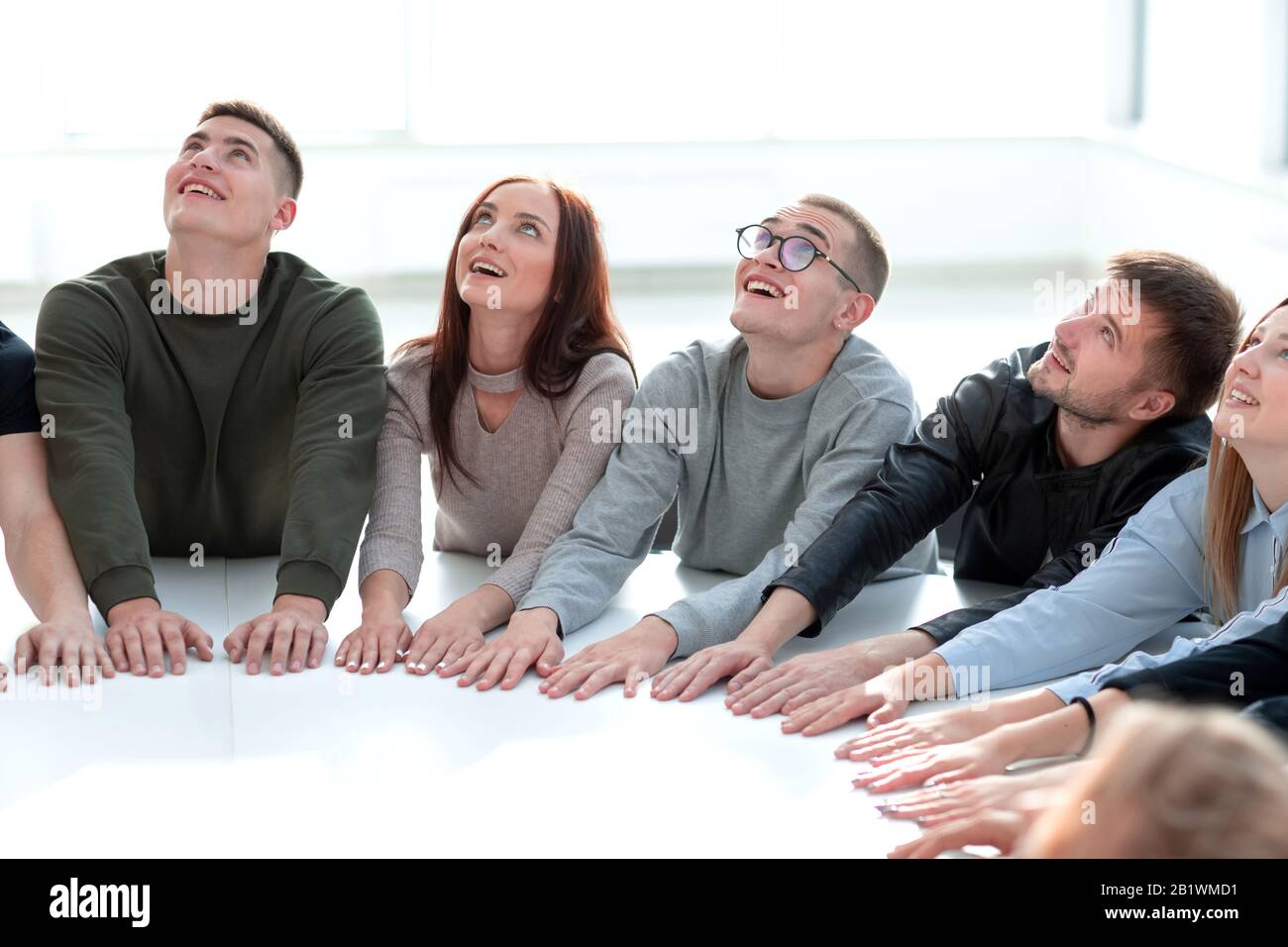 group of young people sitting at a table and looking up Stock Photo - Alamy