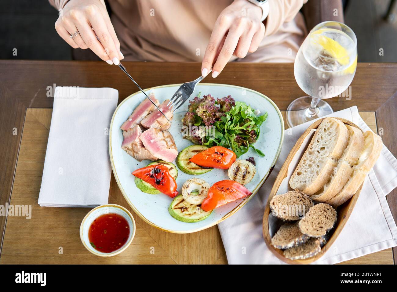Woman eat Medium rare tuna with lettuce and hot sauce. Lunch in a cafe ...