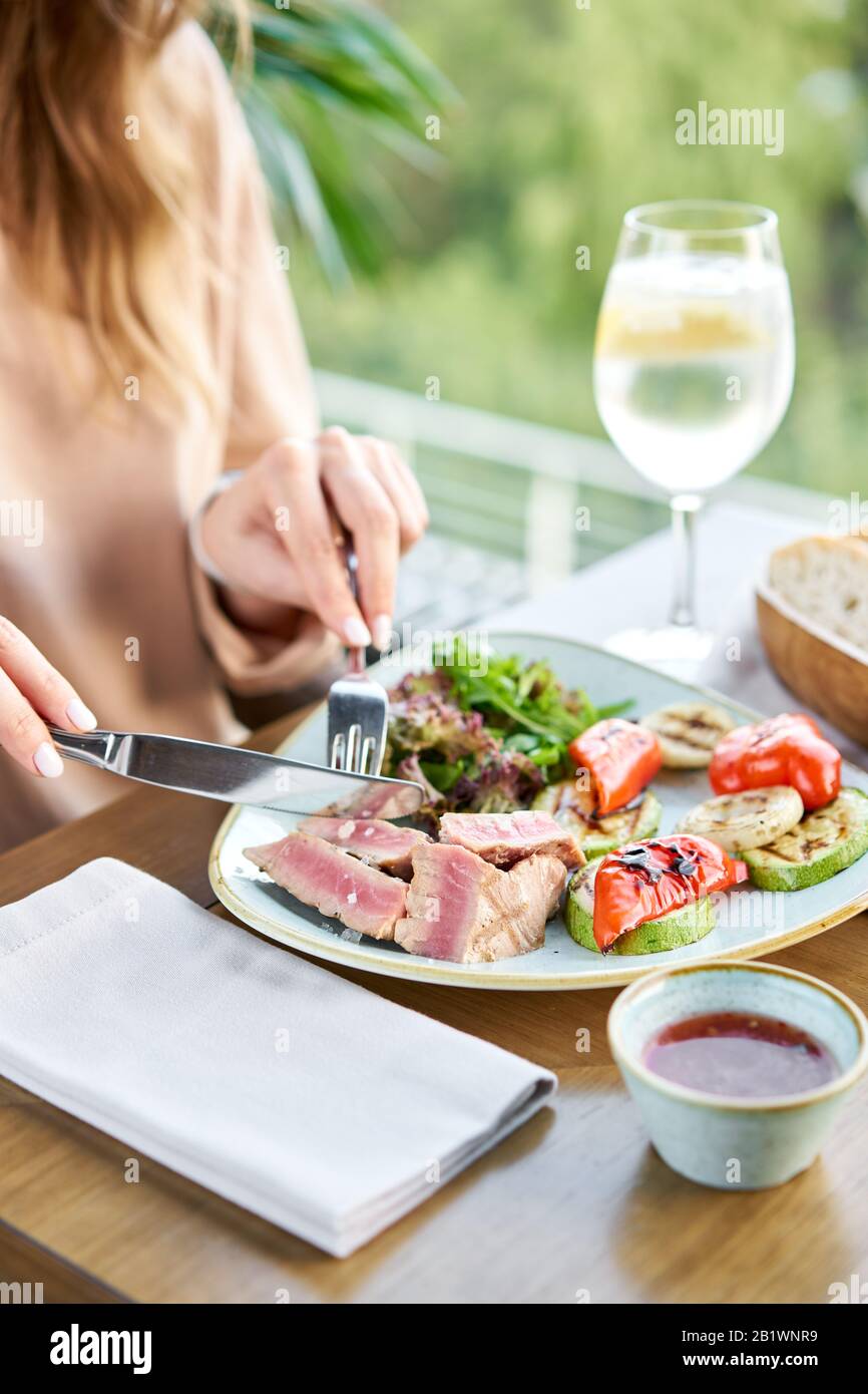 Woman eat Medium rare tuna with lettuce and hot sauce. Lunch in a cafe ...