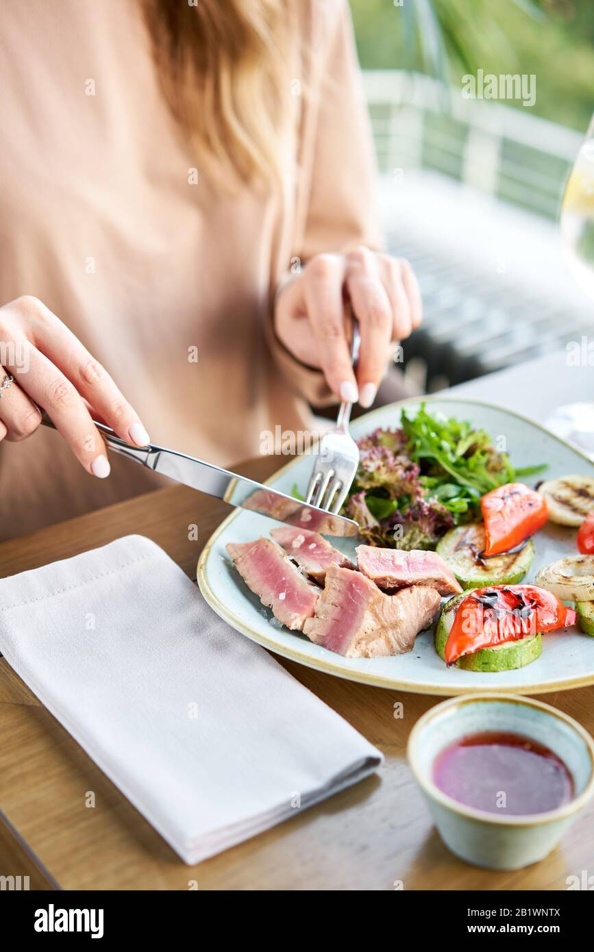 Woman eat Medium rare tuna with lettuce and hot sauce. Lunch in a cafe ...