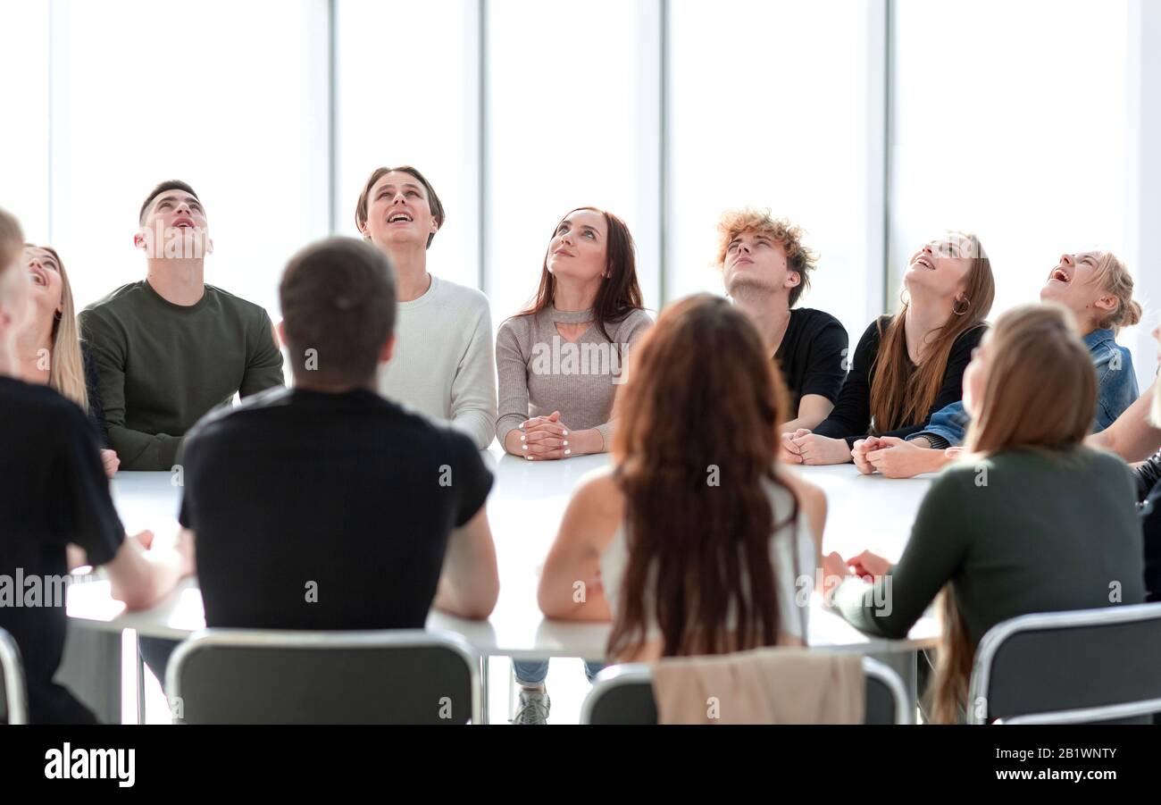 focused group of young people sitting at a round table Stock Photo - Alamy