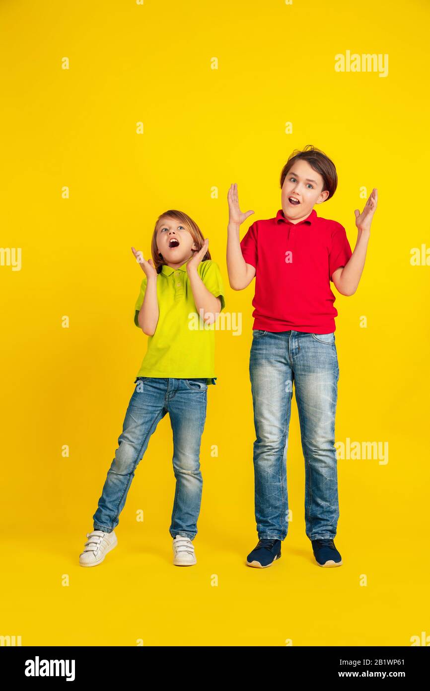 Astonished. Happy children playing and having fun together on yellow ...