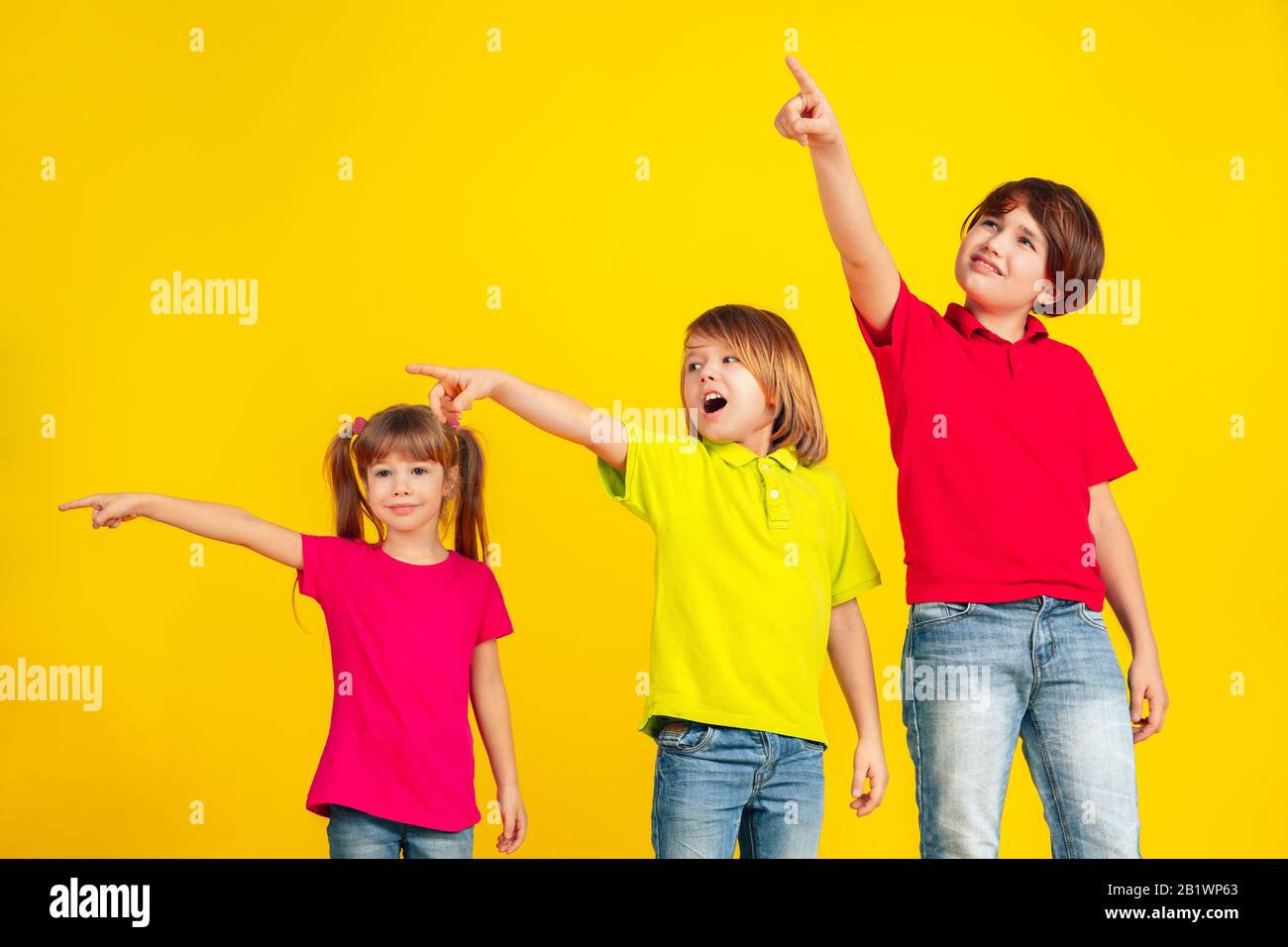Pointing. Happy children playing and having fun together on yellow ...