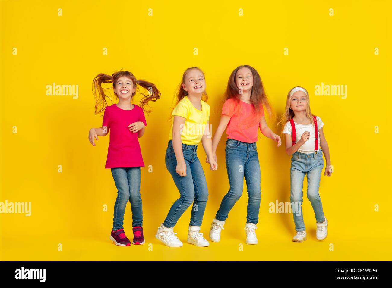 Jumping. Happy children playing and having fun together on yellow ...
