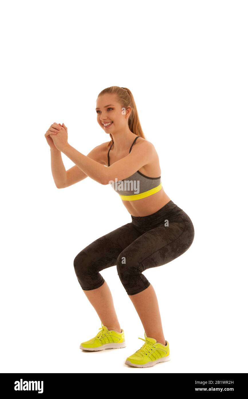 Beautiful young fit woman makes squats isolated over white background ...