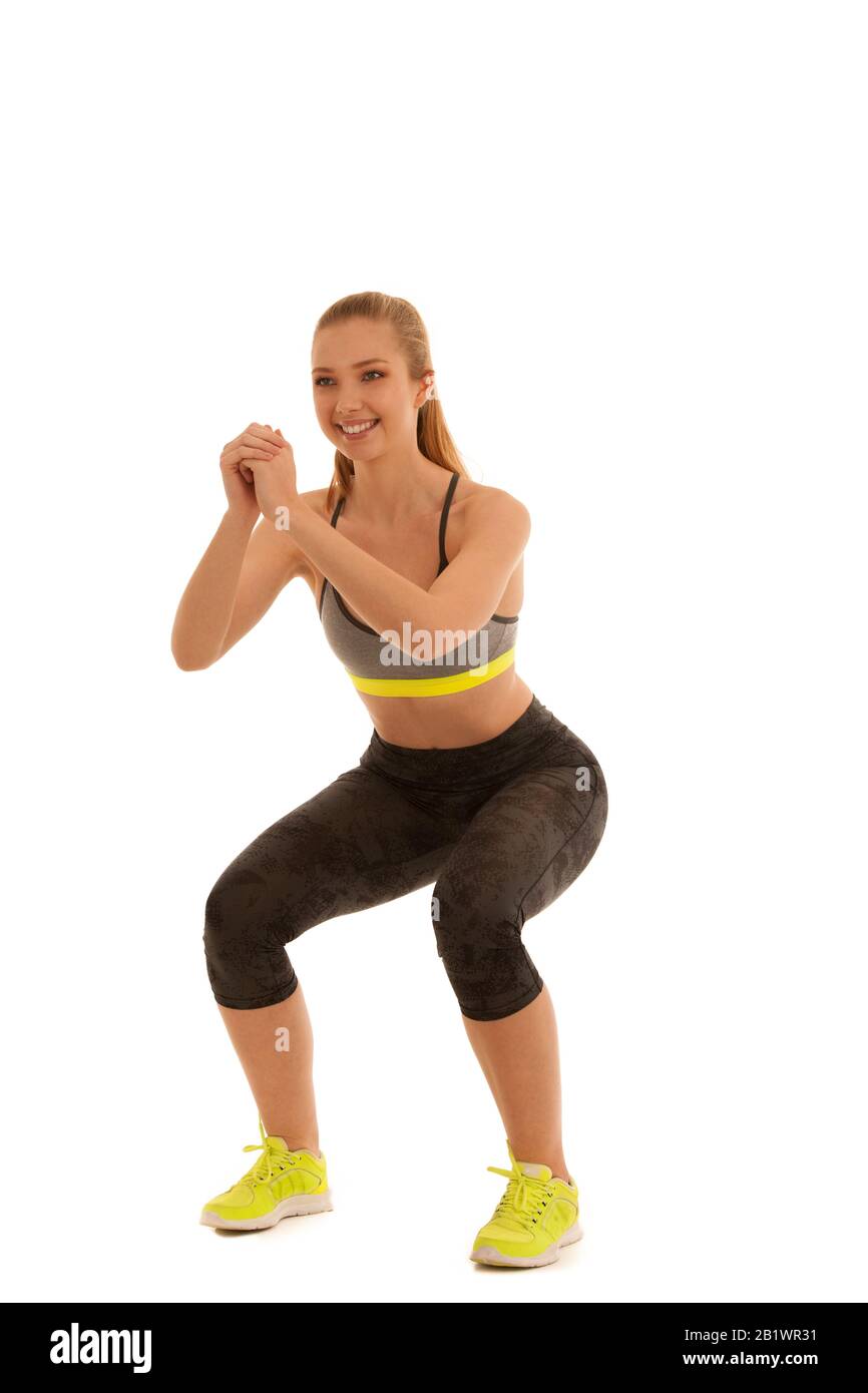 Beautiful young fit woman makes squats isolated over white background ...