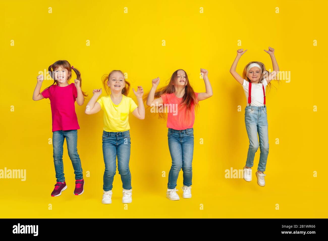 Jumping. Happy children playing and having fun together on yellow ...