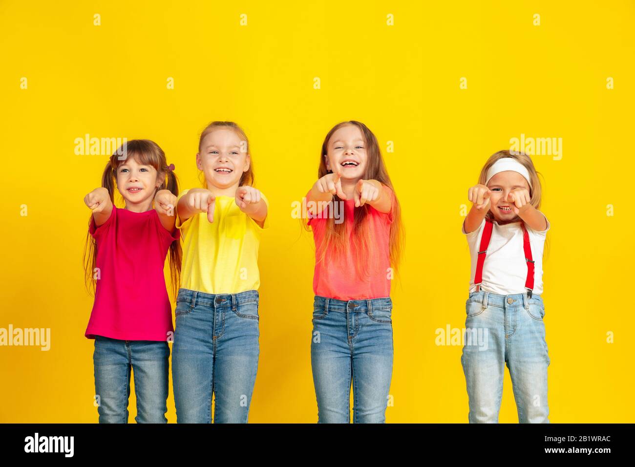 Pointing. Happy children playing and having fun together on yellow ...