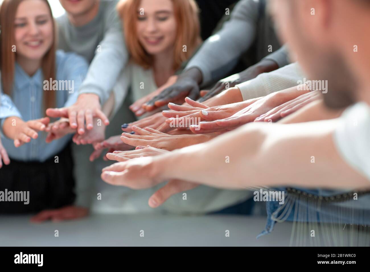 group of smiling young people joining their hands Stock Photo - Alamy