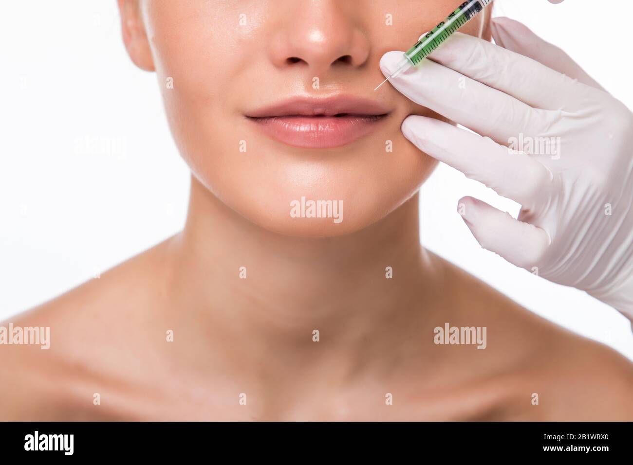 Closeup of beautiful woman gets injection in her lips. Isolated over ...